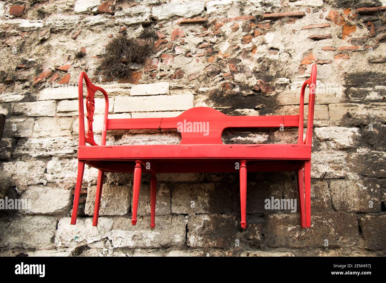 Red chair bench attached to a wall on display Stock Photo - Alamy