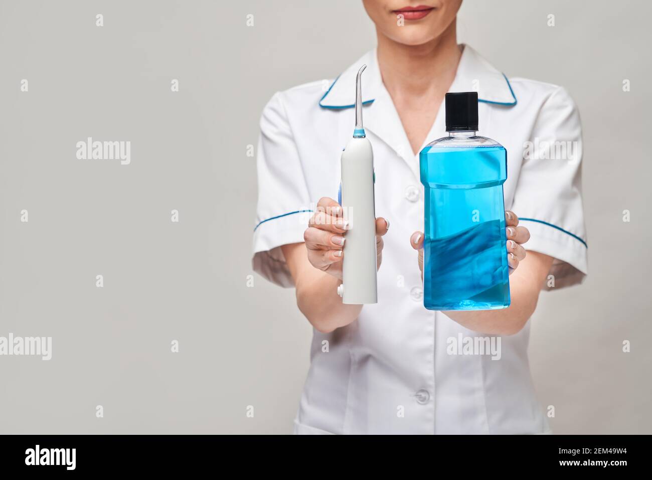 woman dentist doctor holding bottle of mouthwash and irrigator standing ...