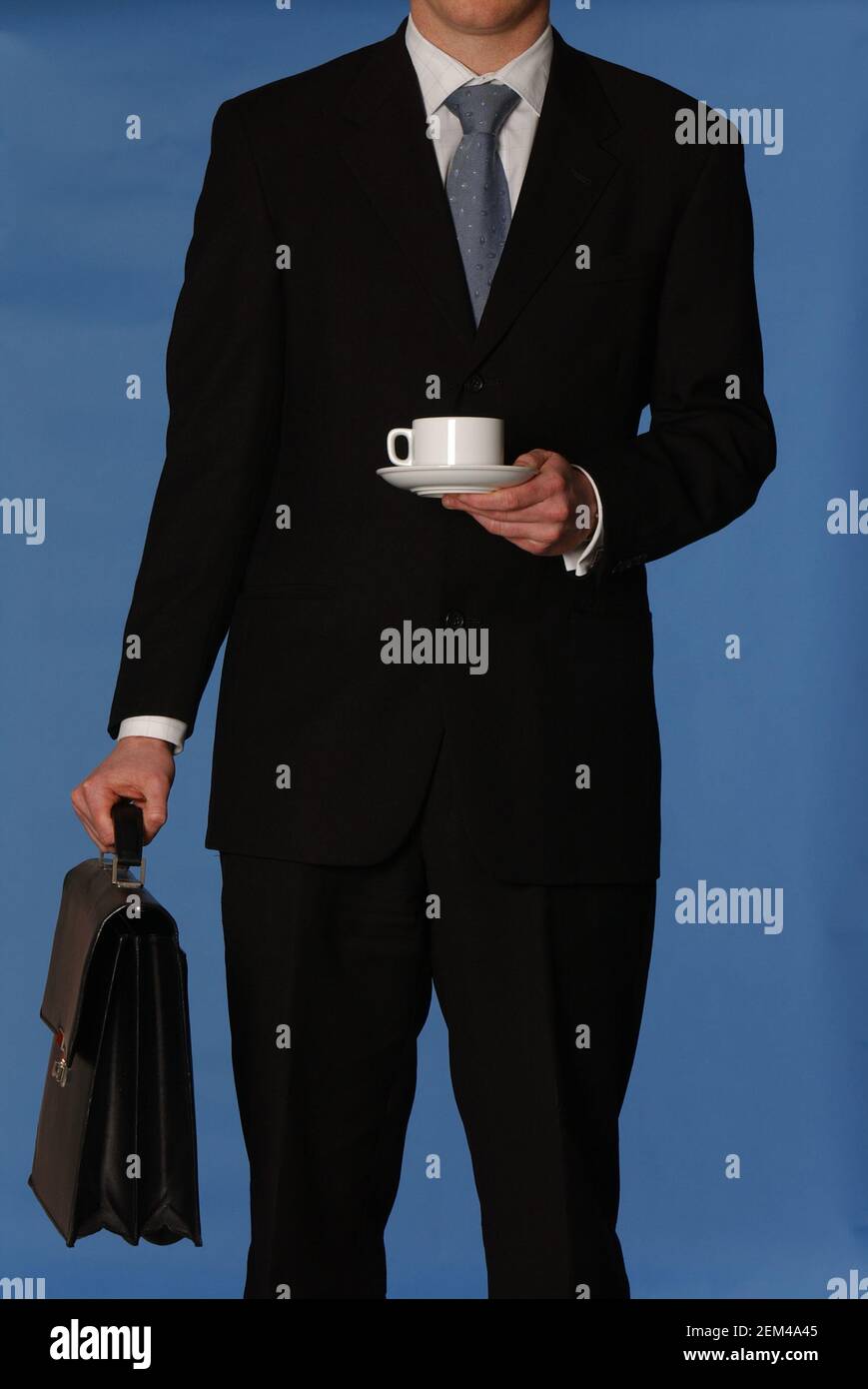 Faceless white business man in a black suit with a blue tie carrying a ...