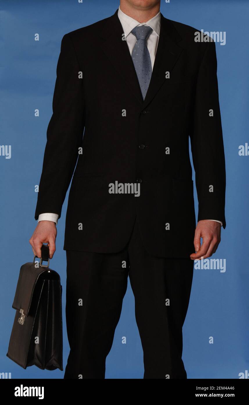 Faceless white business man in a black suit with a blue tie carrying a ...