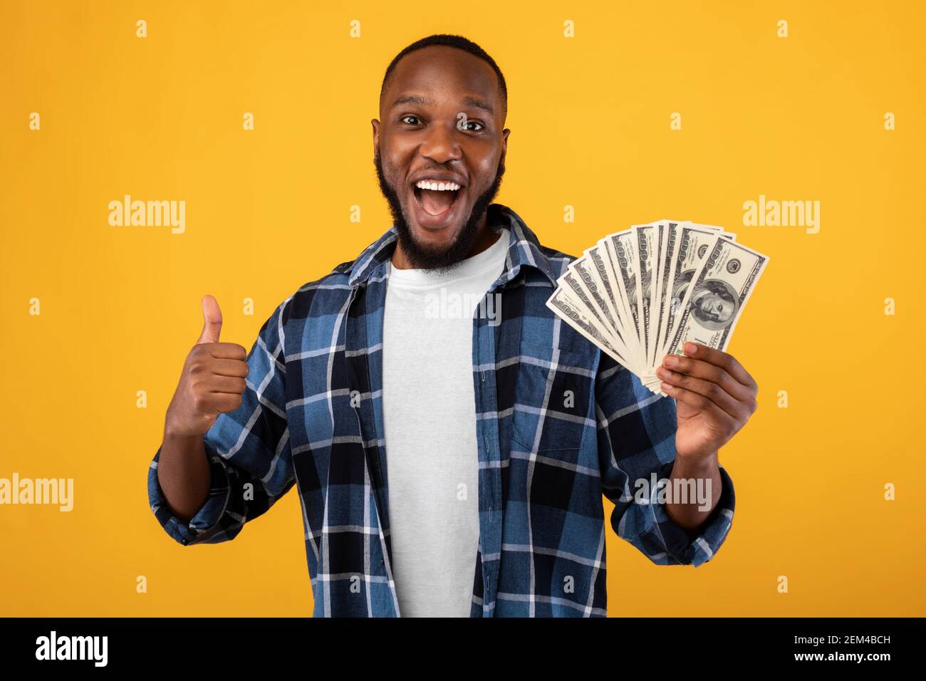 Joyful Black Guy Holding Money Cash Gesturing Thumbs-Up, Yellow ...