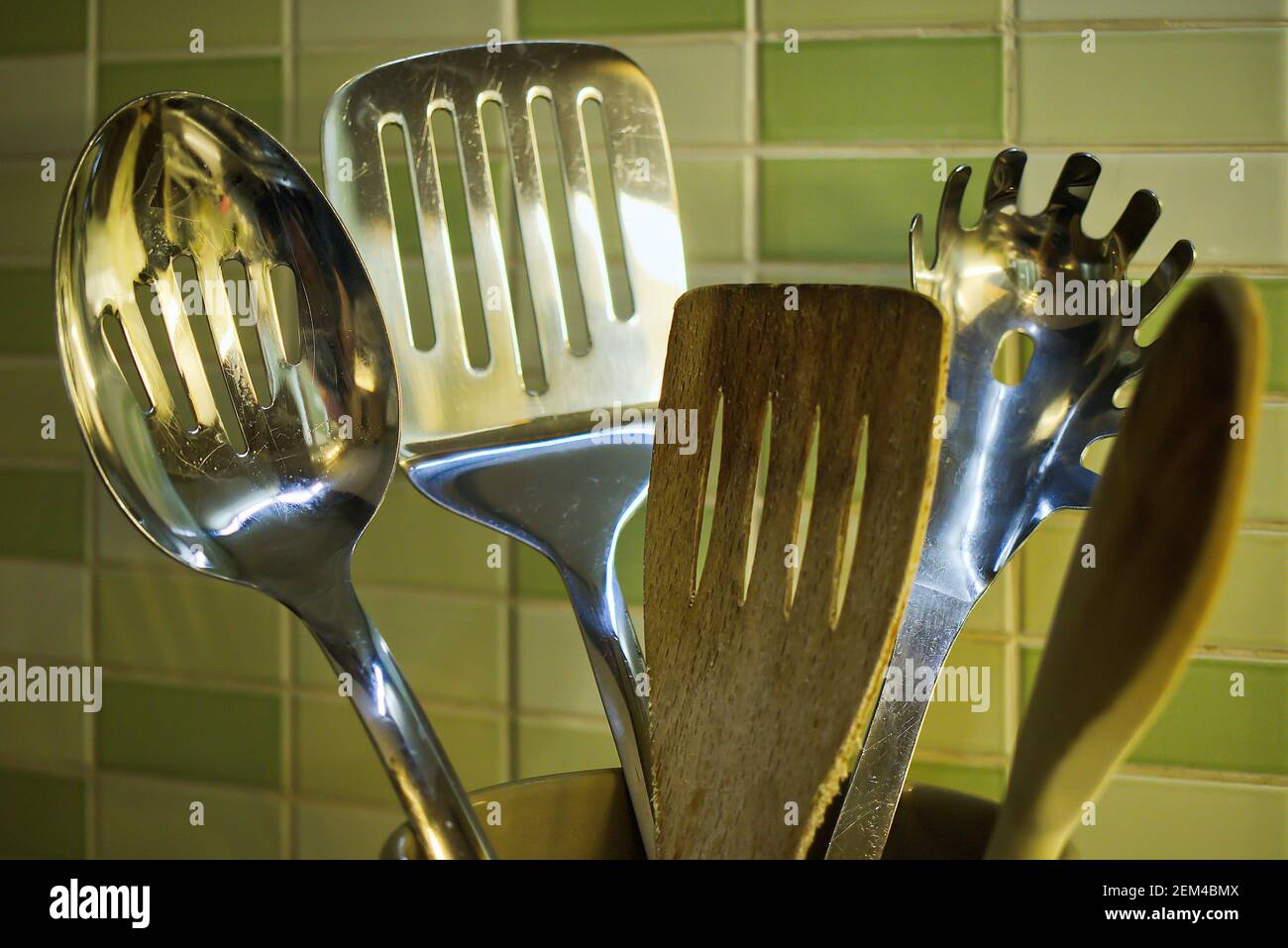 Kitchen utensils in a ceramic pot - wooden spoon, spatula and stainless ...