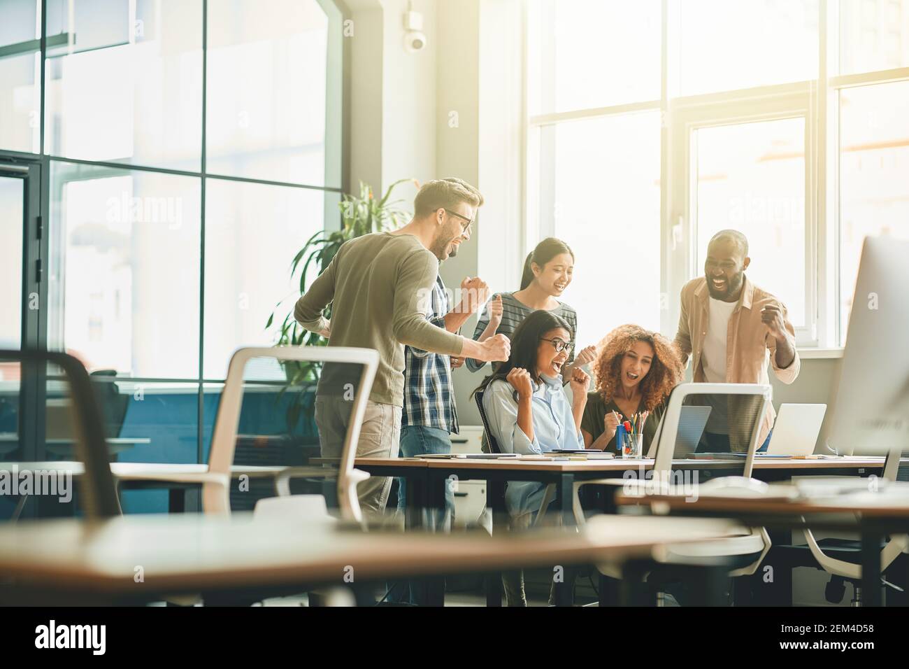 Energetic young people celebrating success of their project at work ...