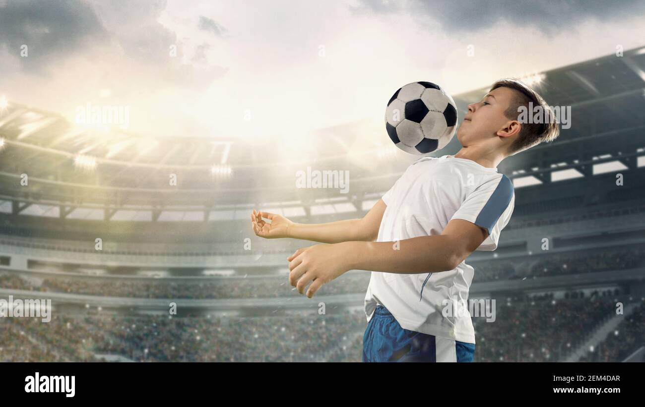 Junior football or soccer player at stadium in flashlight. Young male ...