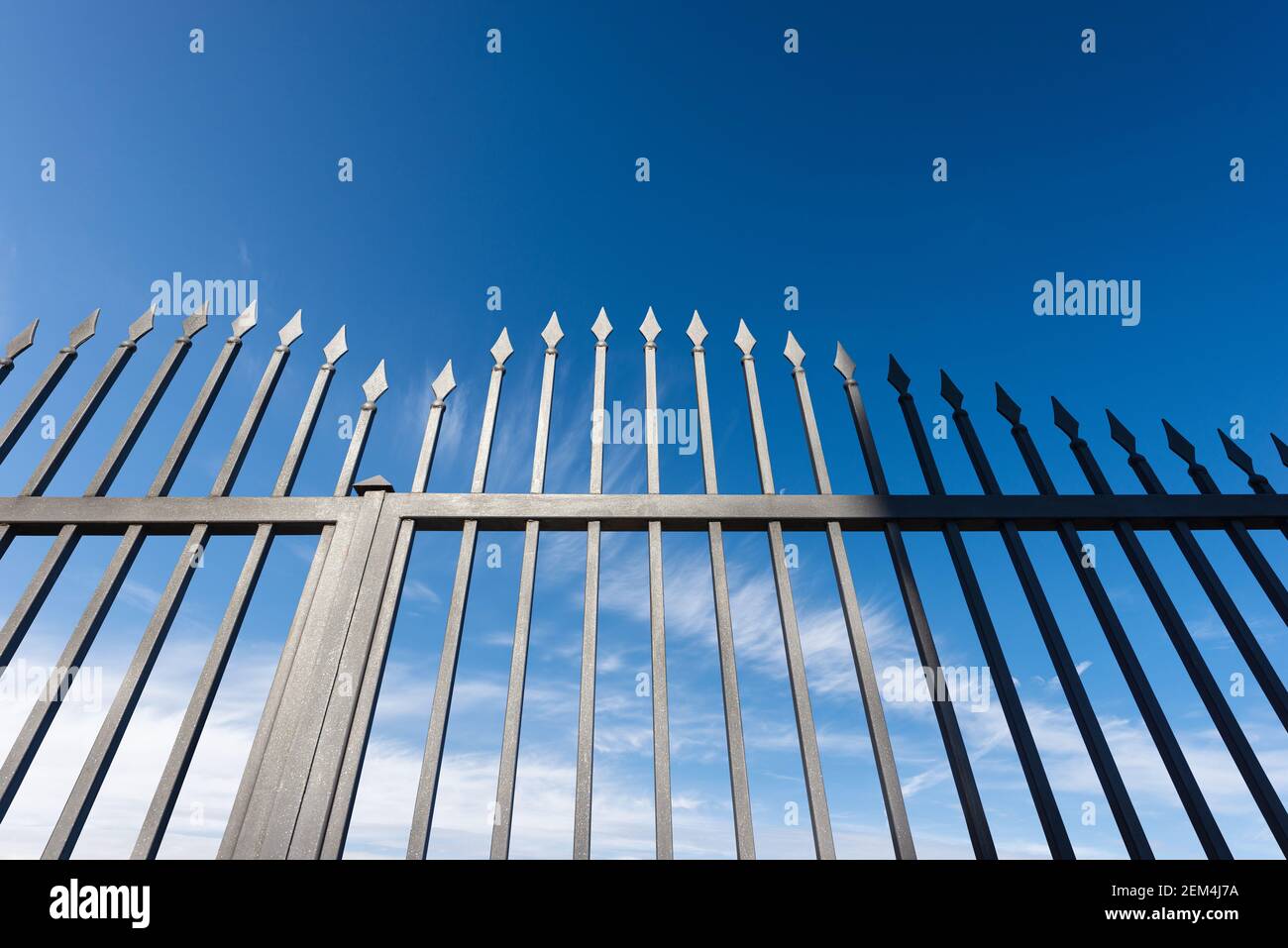 Closeup of a wrought iron gate with sharp points on blue sky with ...