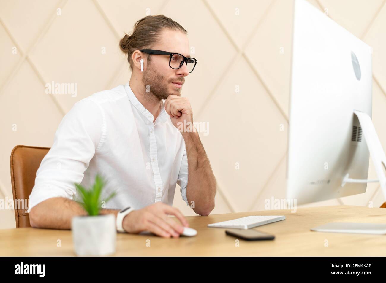 Mature man sitting at the computer, seriously looking at the screen ...