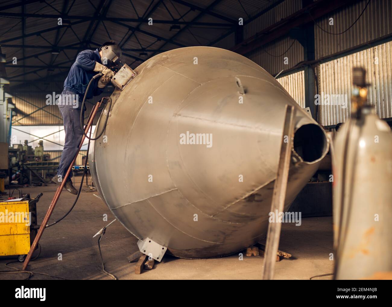 Side view of professional focused mask protected welder man in uniform ...