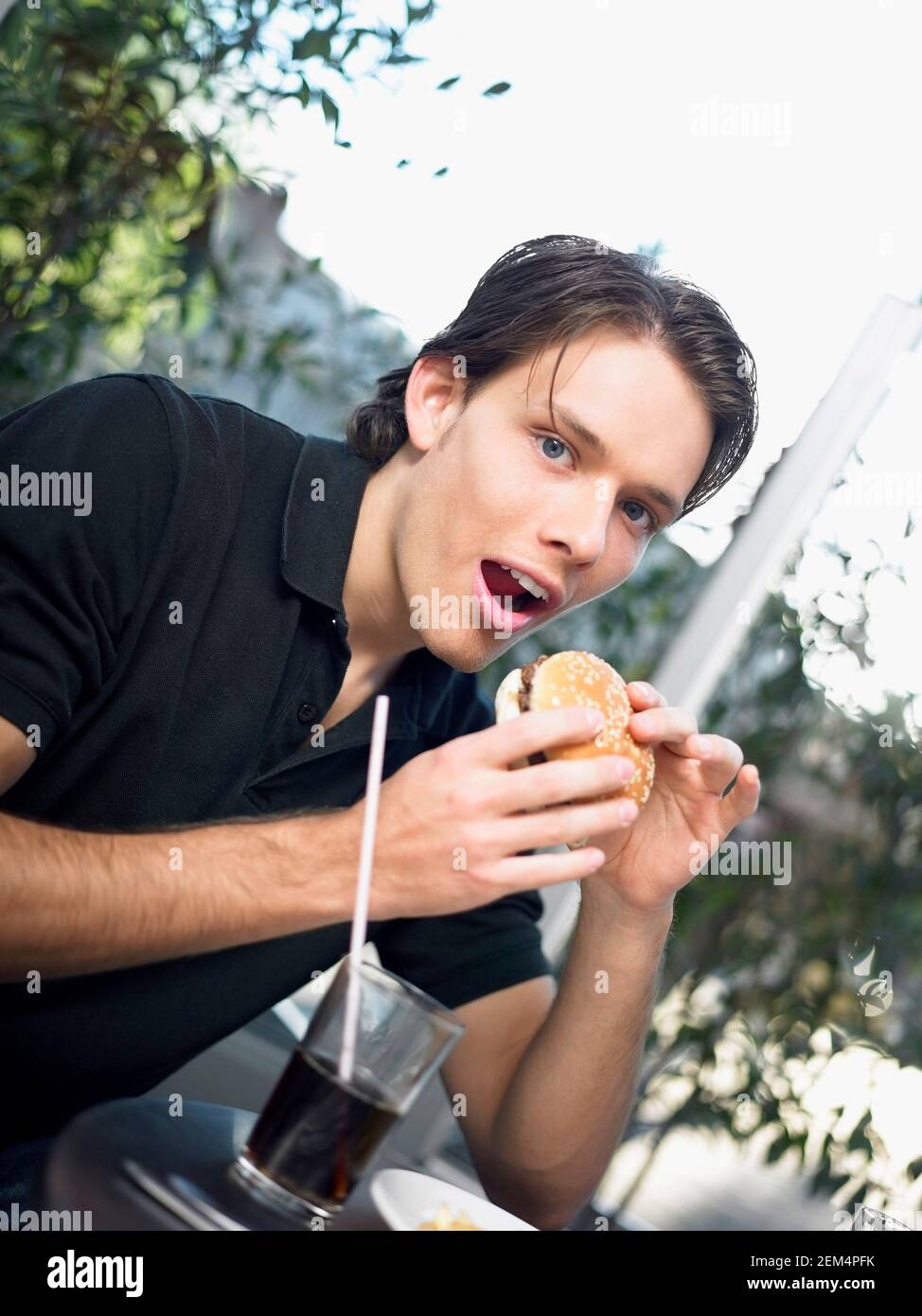 Portrait of a young man eating a burger Stock Photo - Alamy