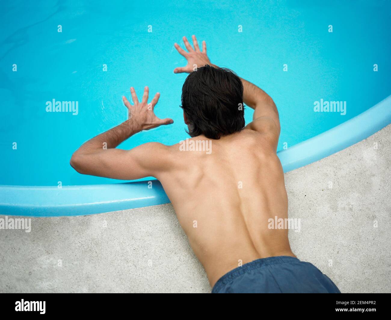 Rear view of a young man lying at the poolside Stock Photo - Alamy