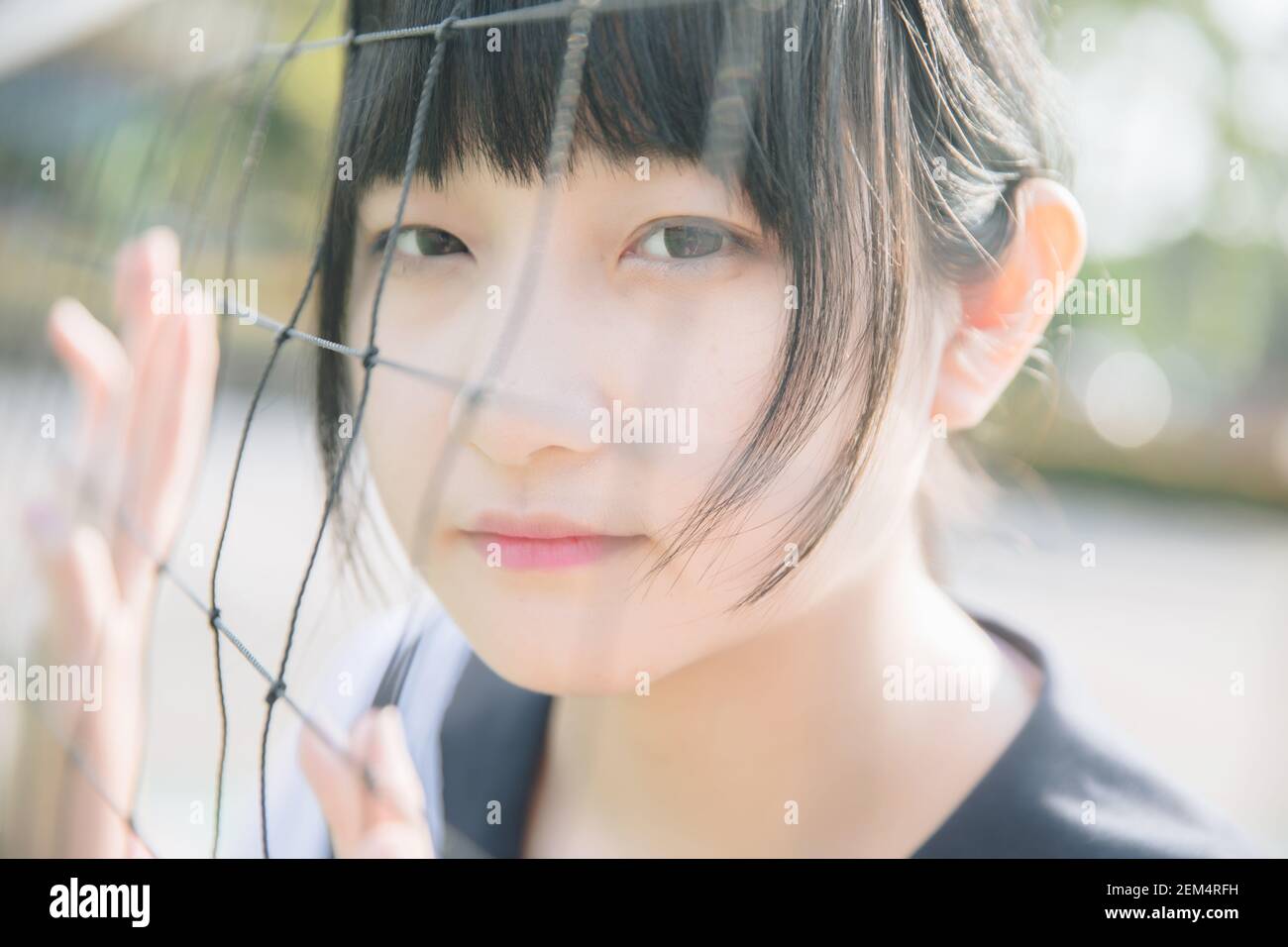 Portrait of beautiful Asian japanese high school girl uniform looking with net in green ...