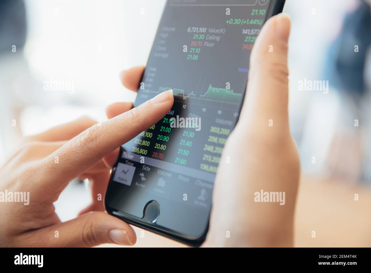 Female hand with smartphone trading stock online in coffee shop ...
