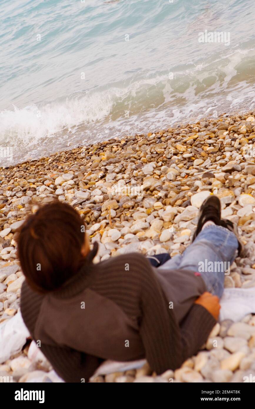 Rear view of a man reclining on the beach Stock Photo - Alamy