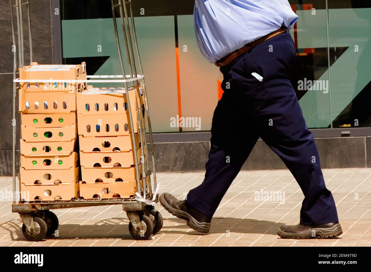 Side profile of a man pushing a stack of crates in a push cart Stock ...