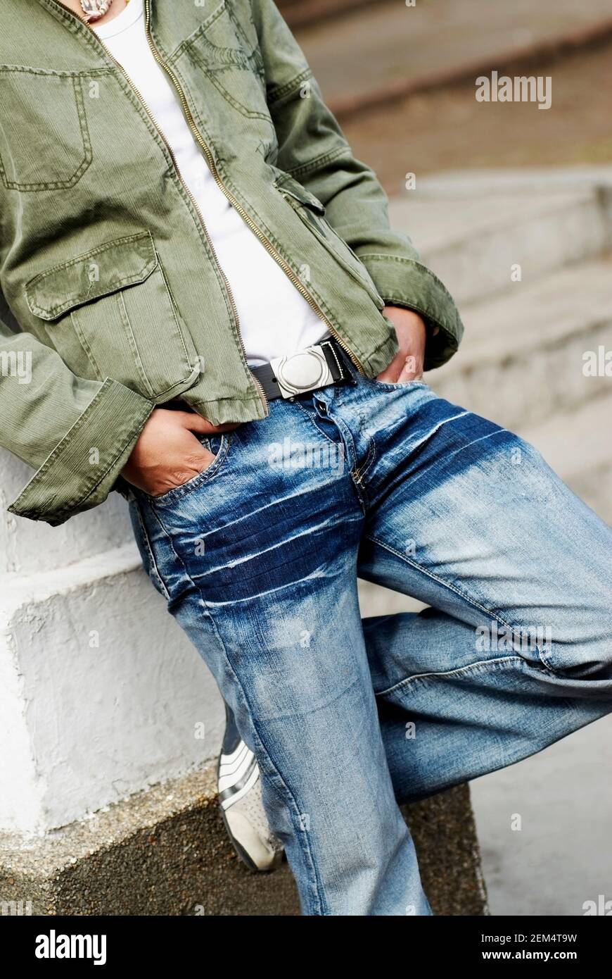 Man leaning against a stone wall with his hands in his pockets Stock ...