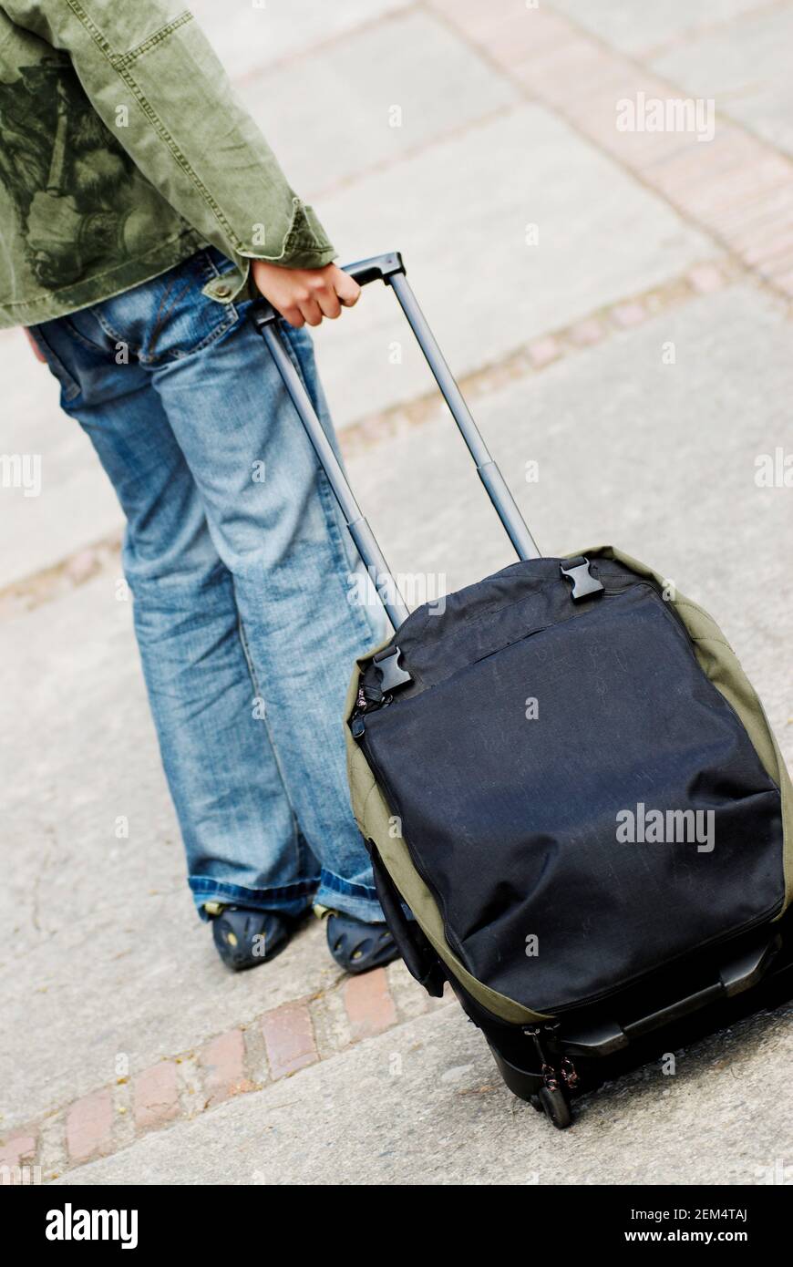 Rear view of a man pulling a suitcase on the road Stock Photo - Alamy