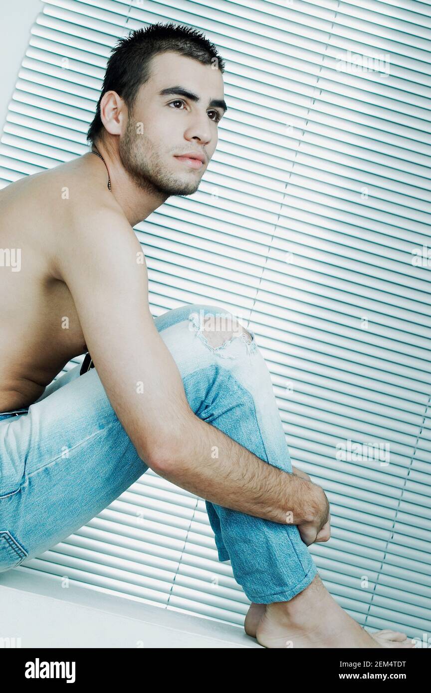 Side profile of a young man sitting on a window sill Stock Photo - Alamy