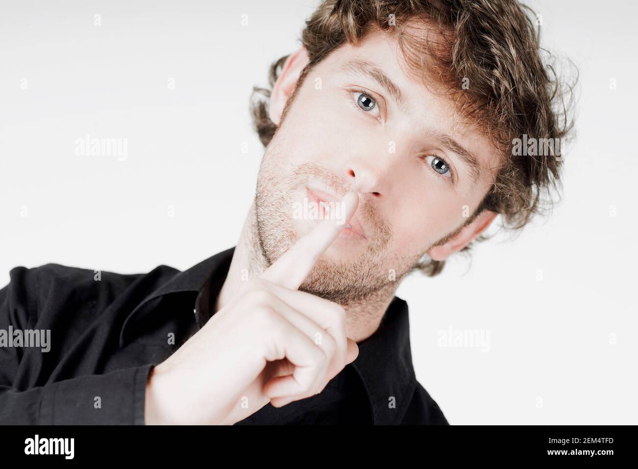 Portrait of a young man with his finger on his lips Stock Photo - Alamy