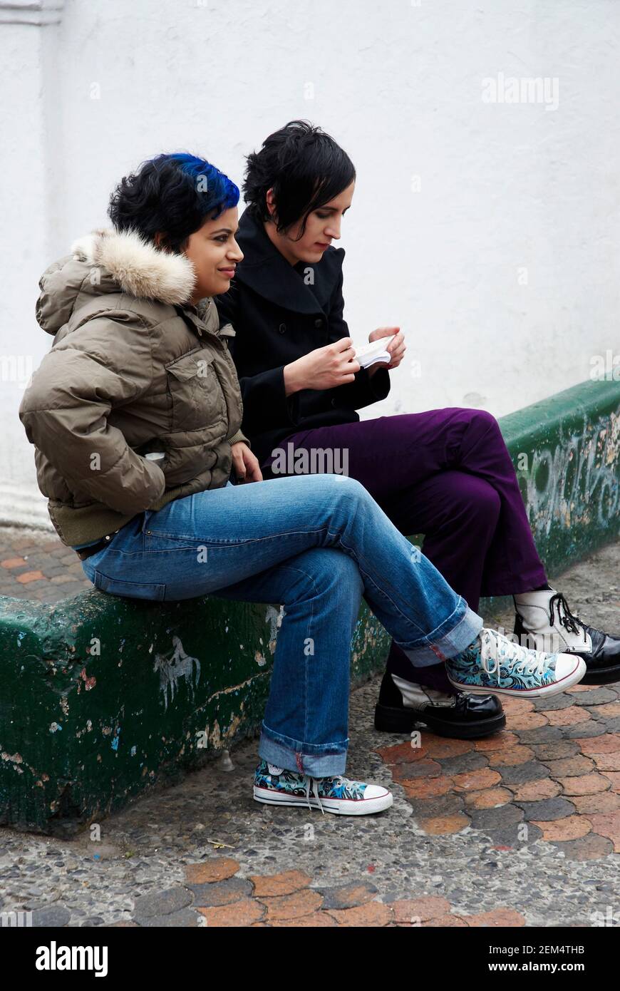 Young couple sitting on a ledge Stock Photo - Alamy