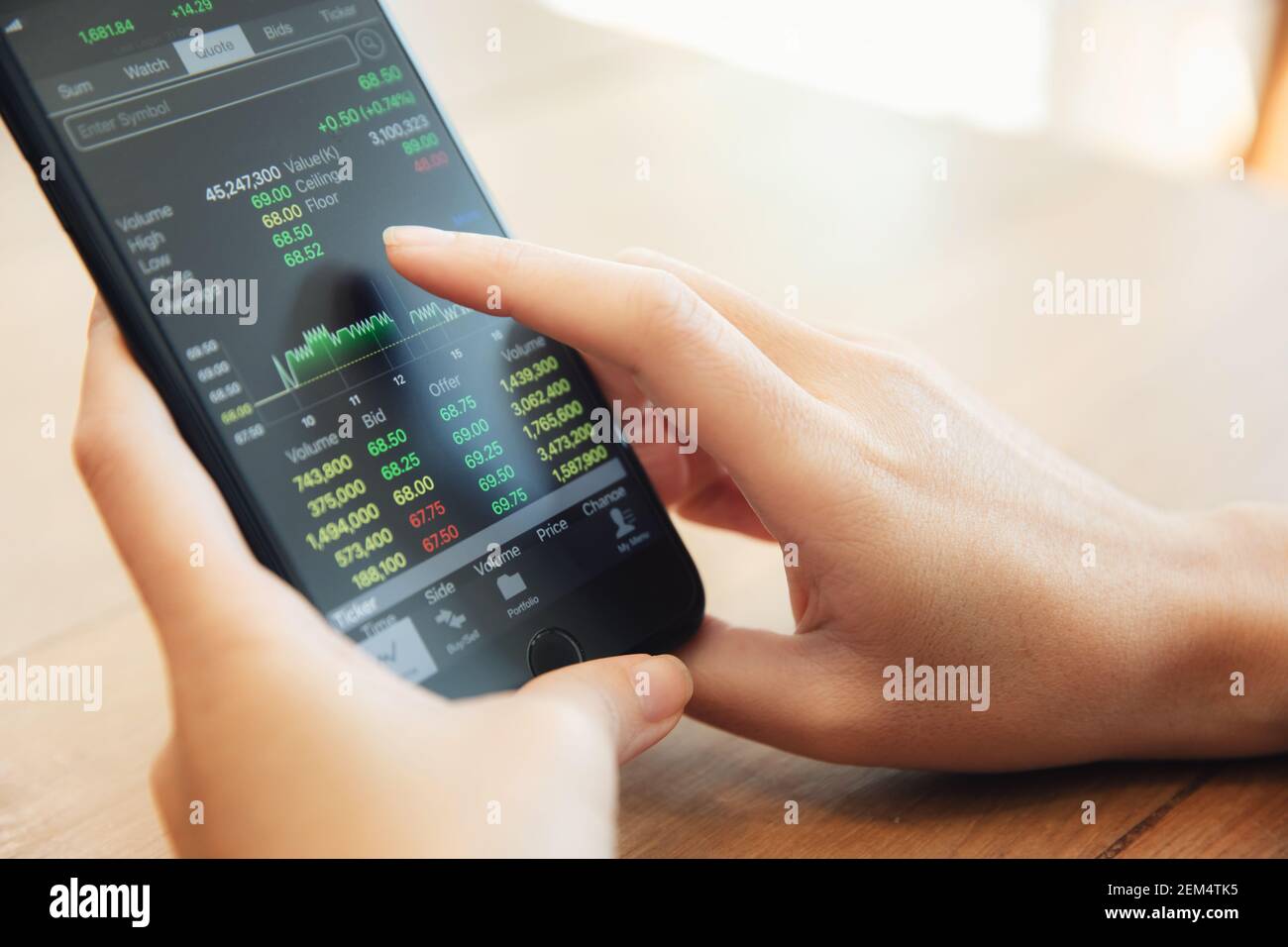 Female hand with smartphone trading stock online in coffee shop ...