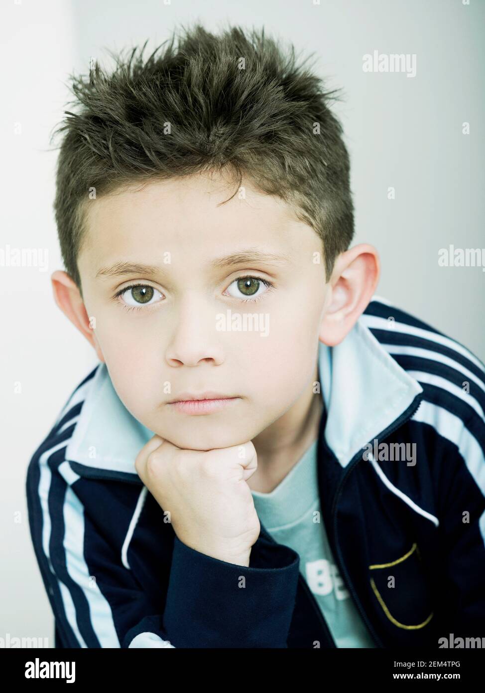 Portrait of a boy sitting with his hand on his chin Stock Photo - Alamy