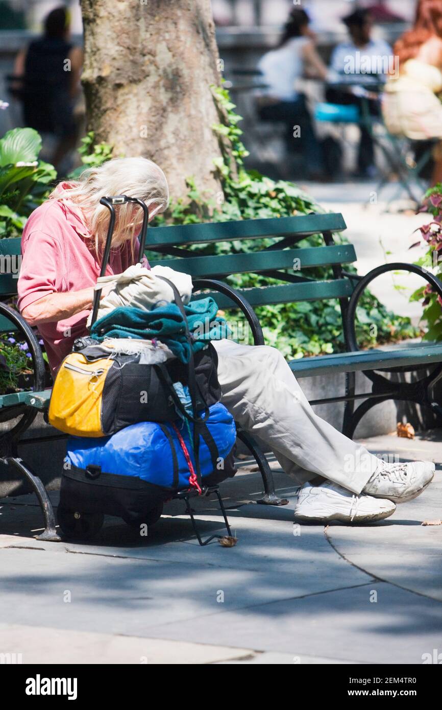 Side profile of a senior woman sitting on a bench and looking down ...