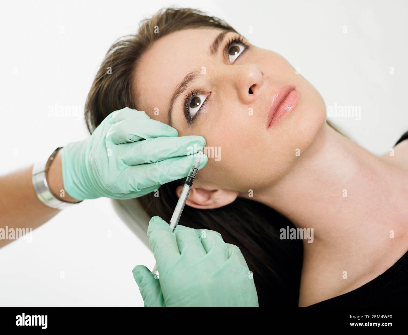 Close-up of a mid adult woman getting a botox injection on her face ...