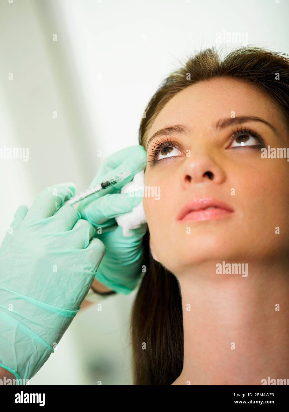 Close-up of a mid adult woman getting a botox injection on her face ...