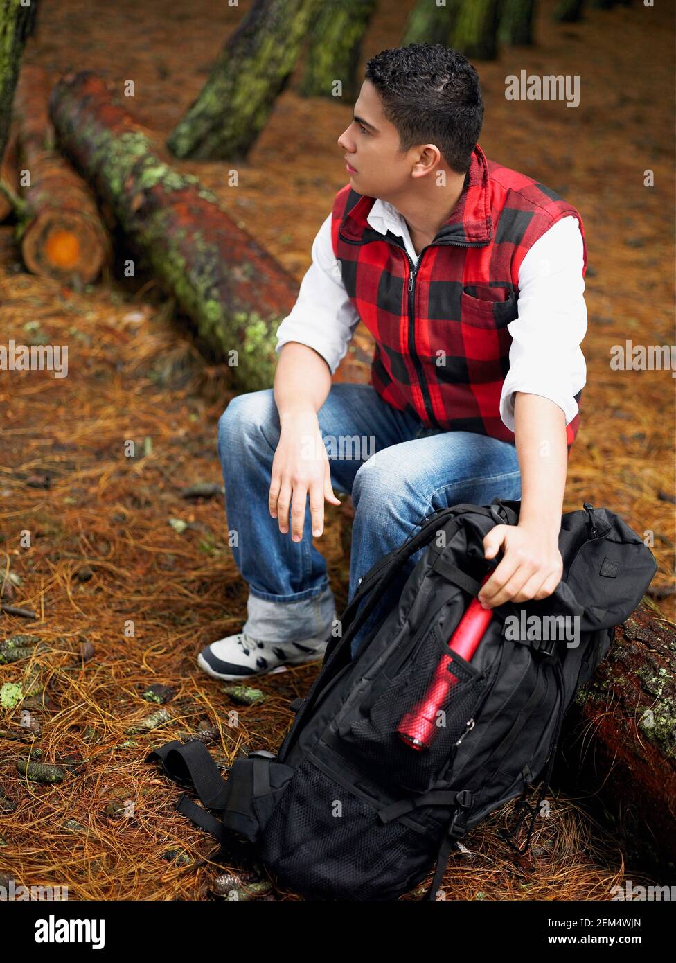 Young man sitting on a tree stump in the forest Stock Photo - Alamy