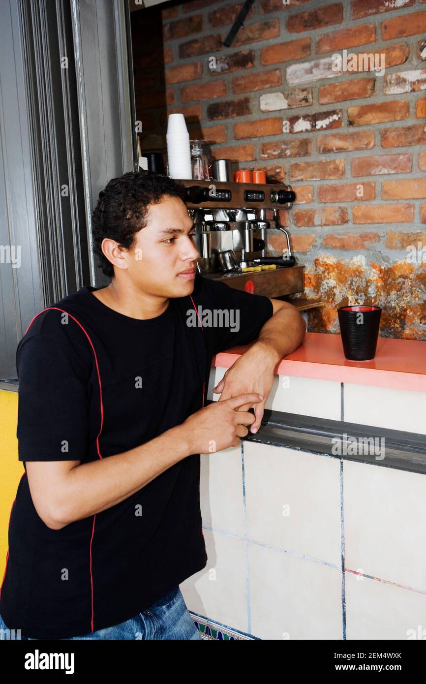 Young man leaning against a cafe checkout counter and thinking Stock ...