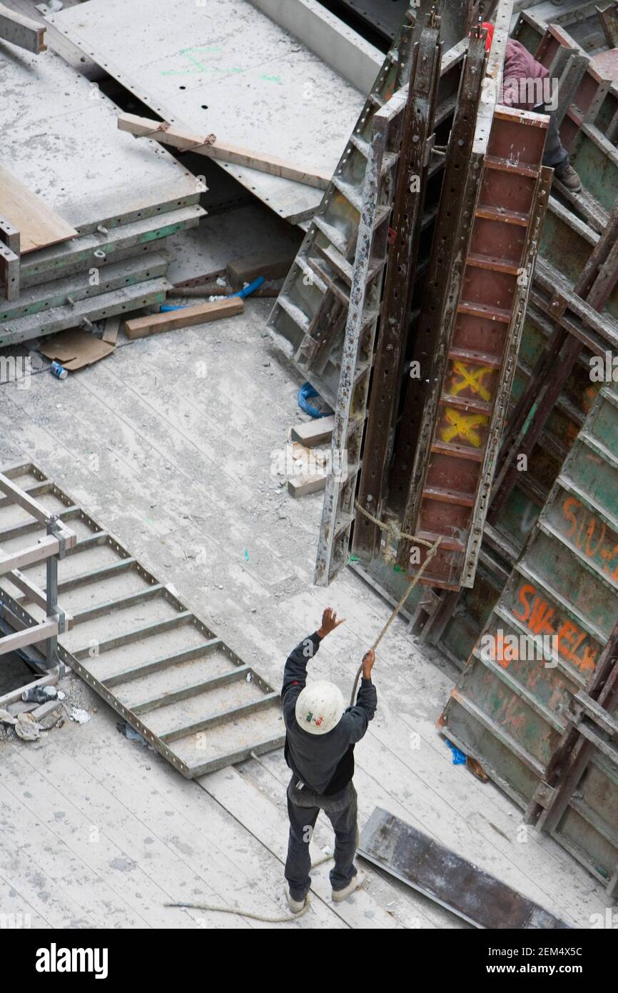 Rear view of two construction workers working at construction site hi ...