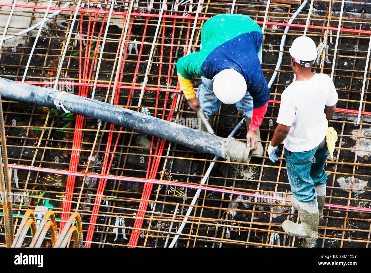 Rear view of two construction workers working at construction site hi ...