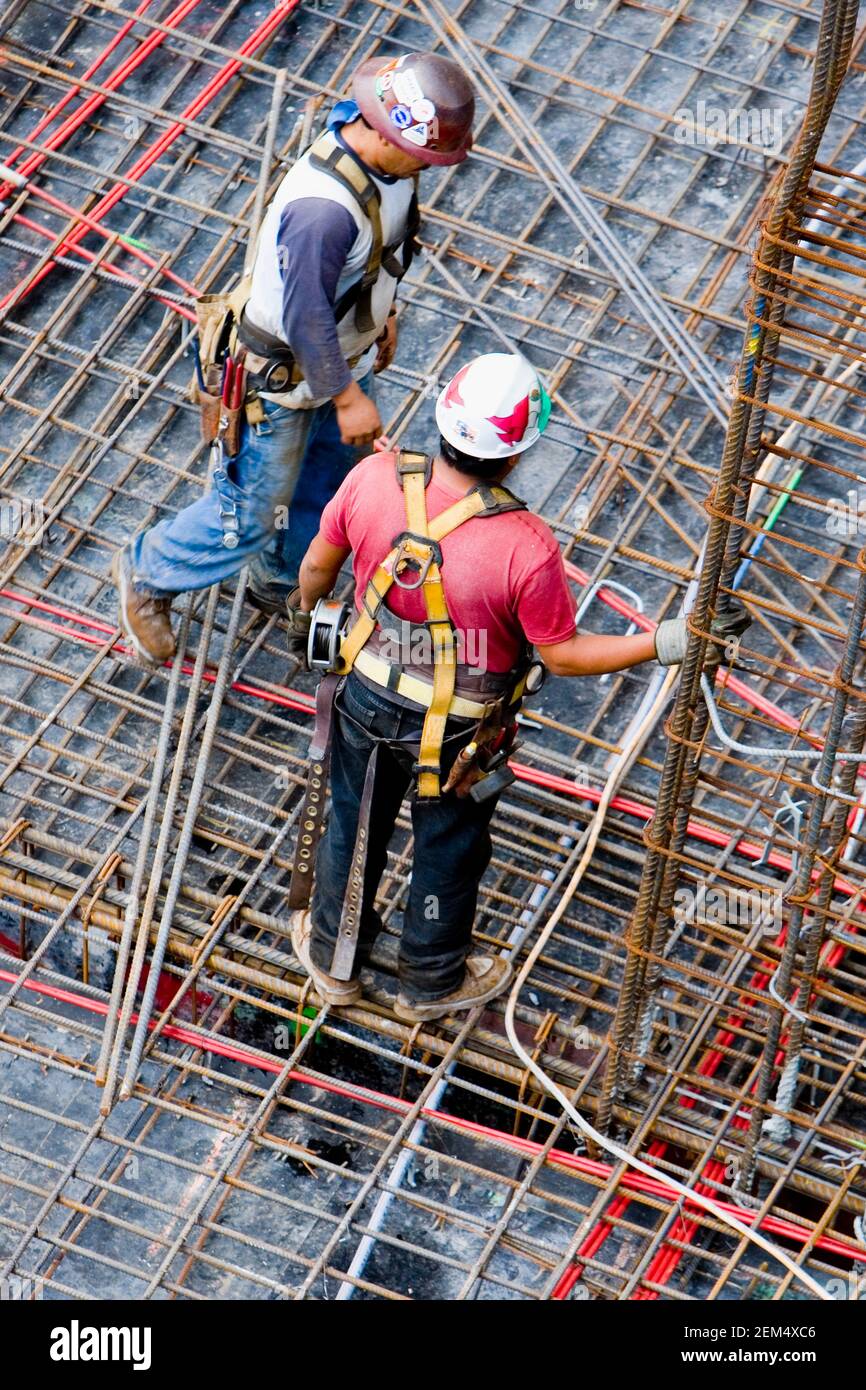 Rear view of two construction workers working at construction site hi ...