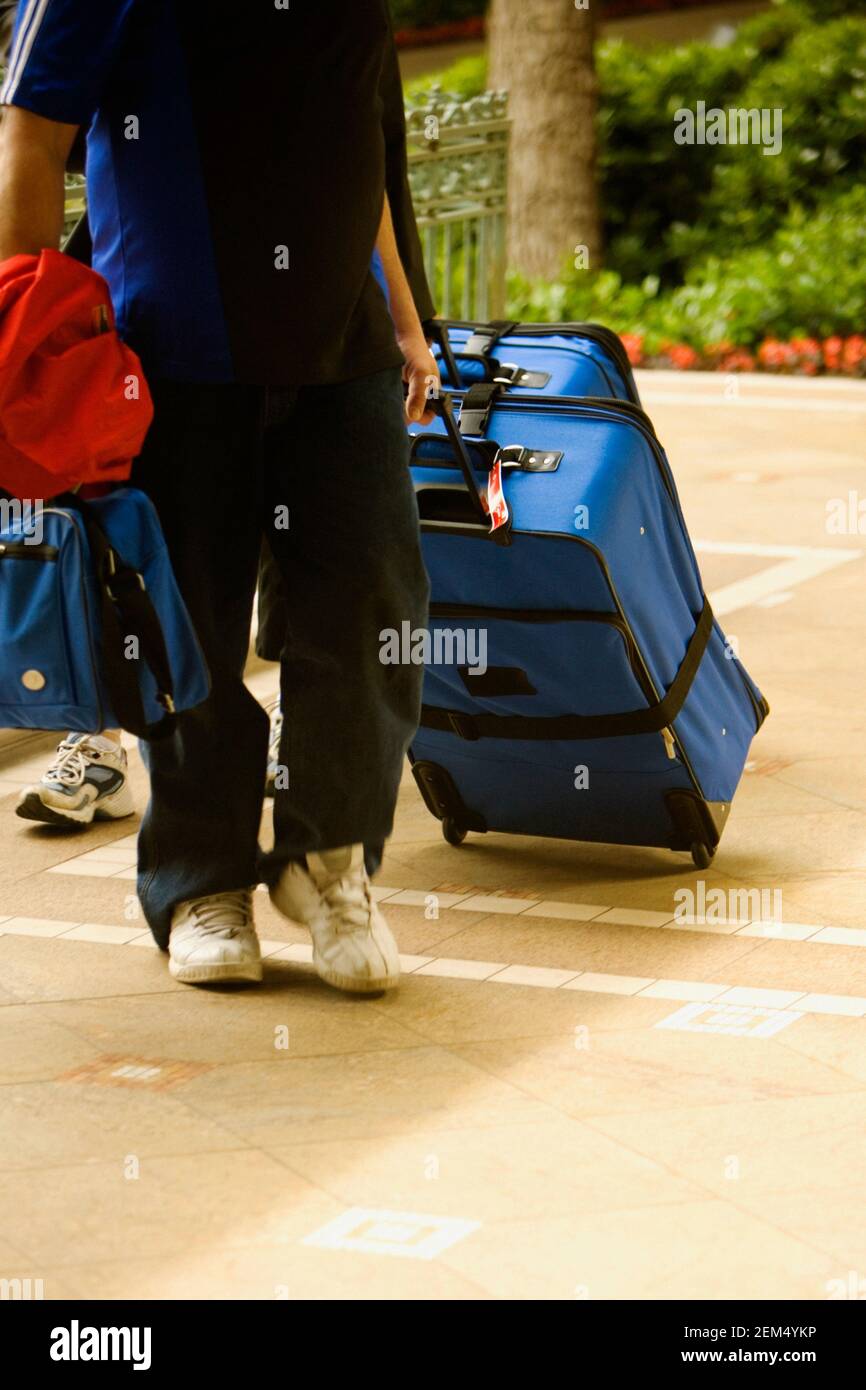 Low section view of a man pulling a suitcase Stock Photo - Alamy