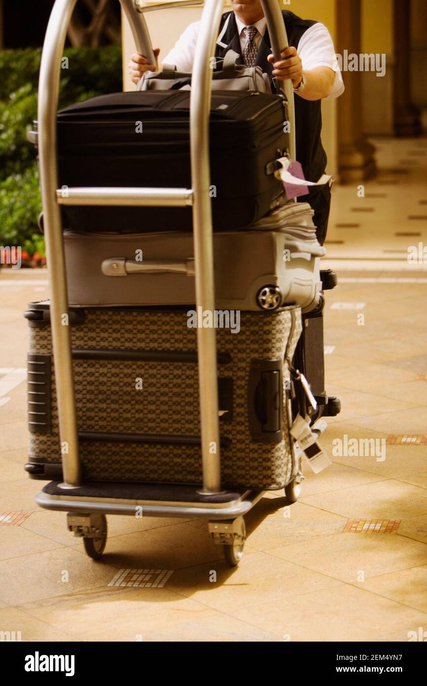 Bellhop pushing a luggage cart Stock Photo - Alamy