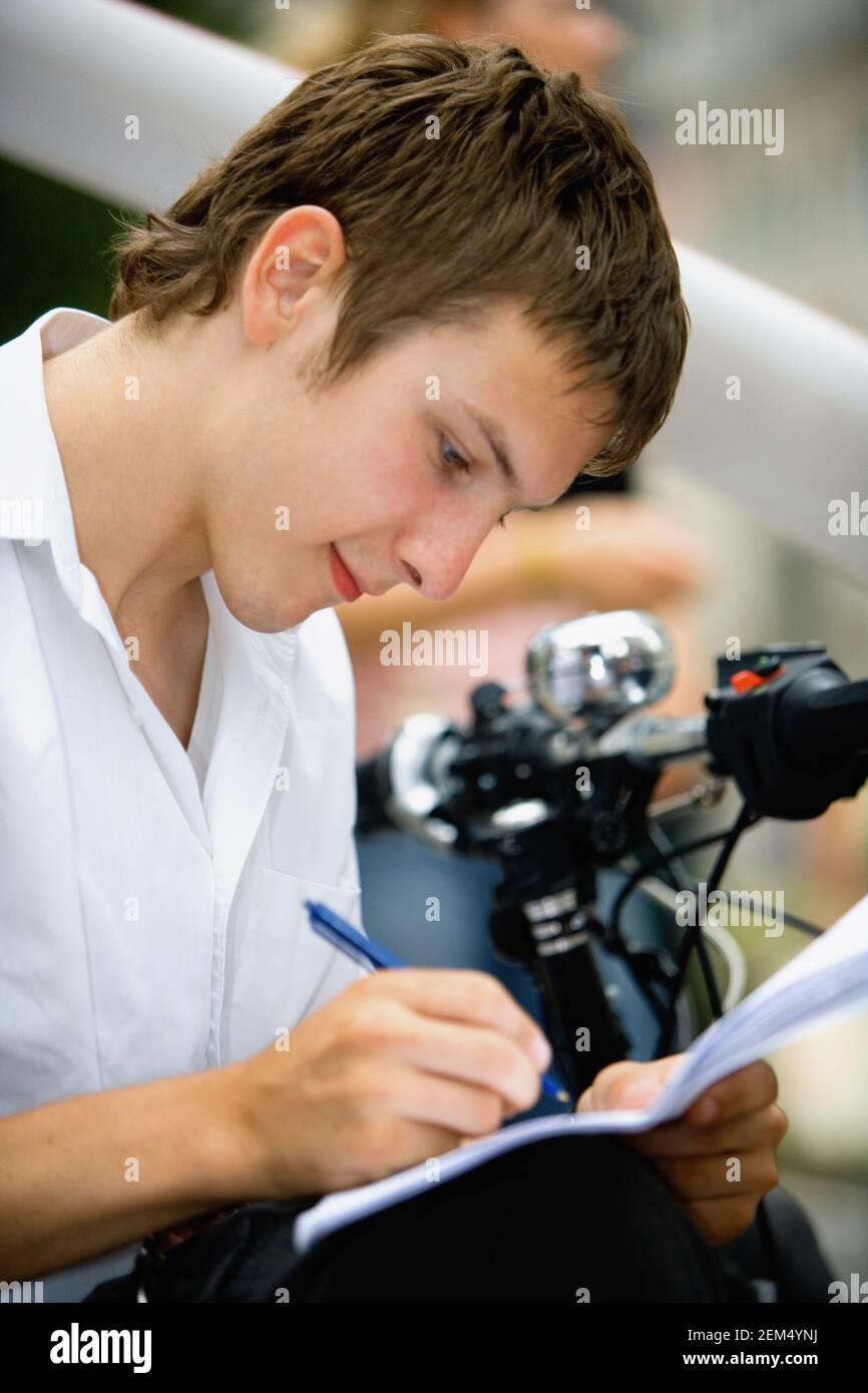 Close-up of a young man writing on paper Stock Photo - Alamy