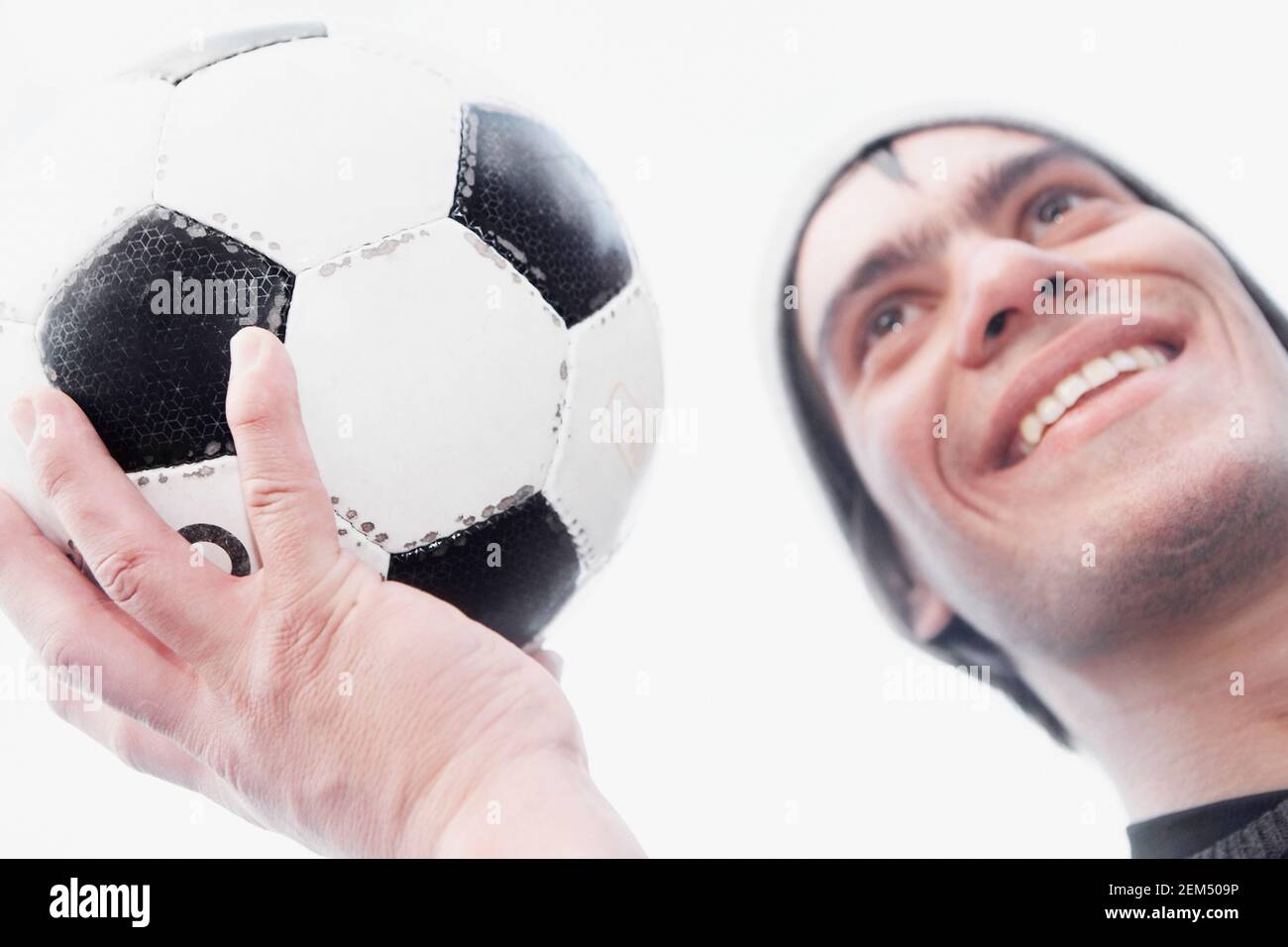 Low angle view of a young man holding a soccer ball in his hand and ...