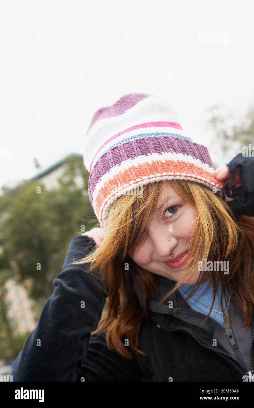 Portrait of a young woman adjusting his hat and smiling Stock Photo - Alamy