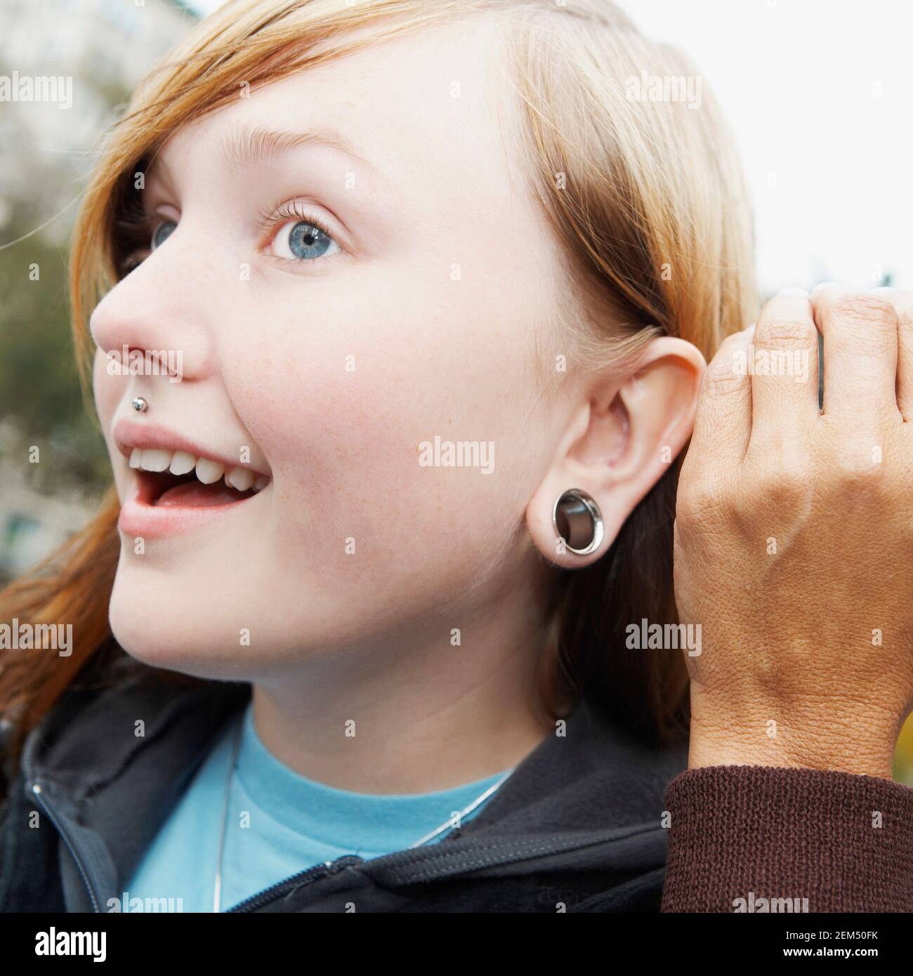 Close-up of a person whispering into a young woman's ears Stock Photo ...