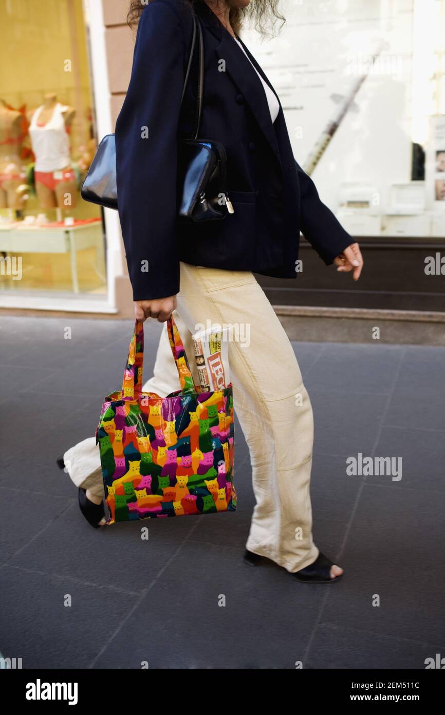 Side profile of a woman carrying a shopping bag and walking Stock Photo ...