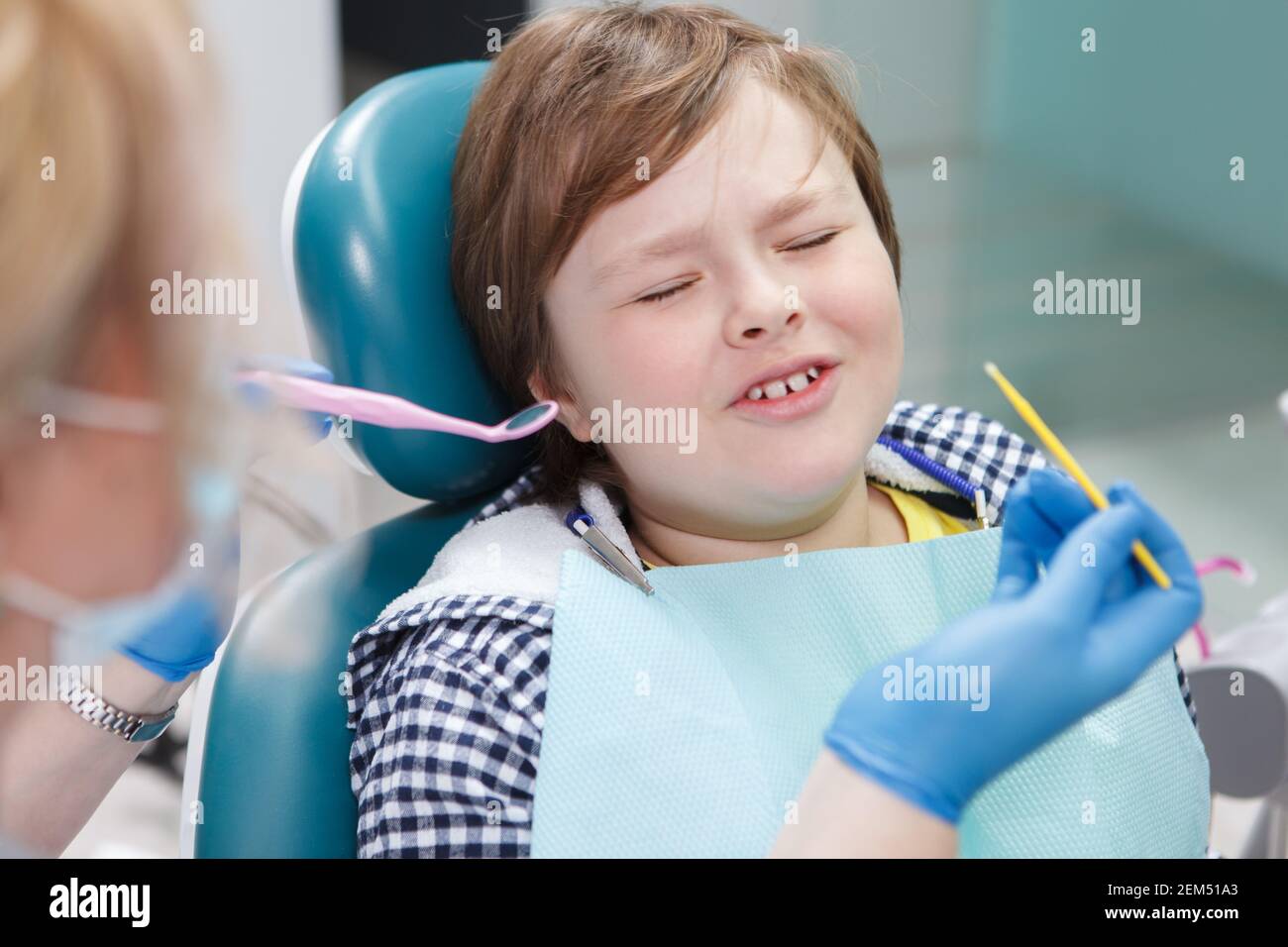 Close up of a young boy whining, sitting in dental chair, having ...