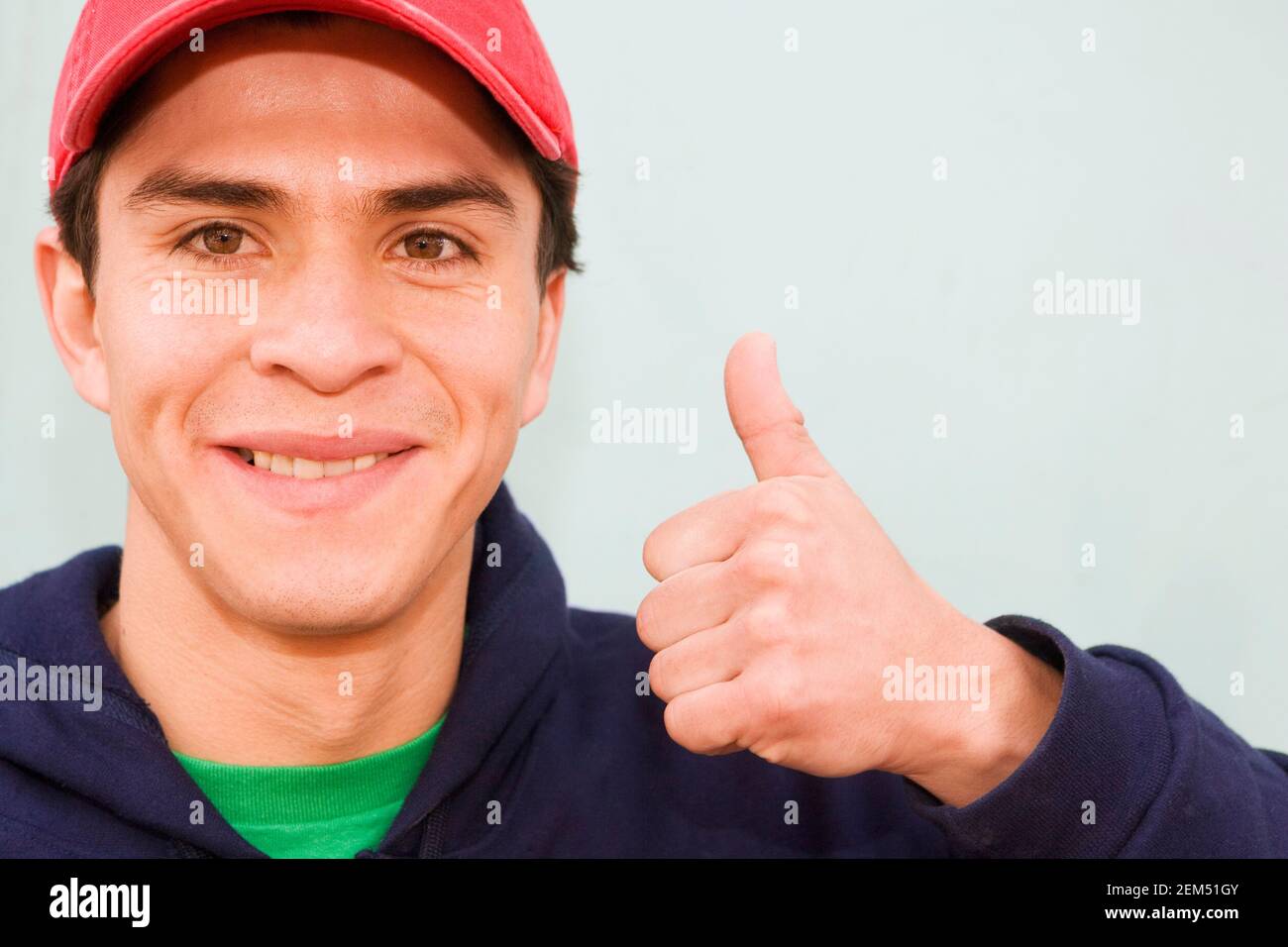 Portrait of a young man showing a thumbs up sign Stock Photo - Alamy
