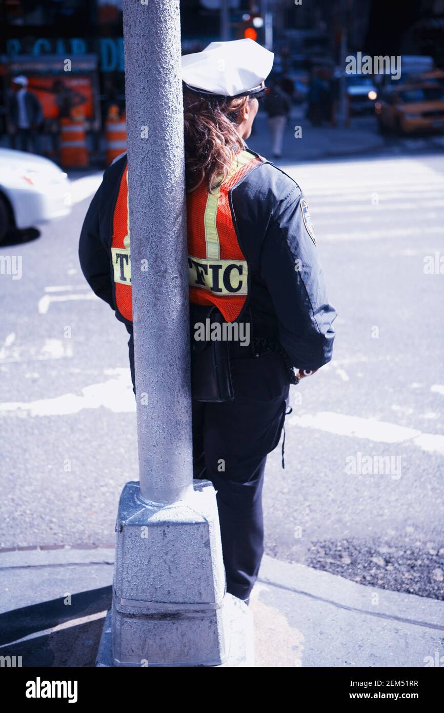 Rear view of a policewoman leaning against a pole, New York City, New ...