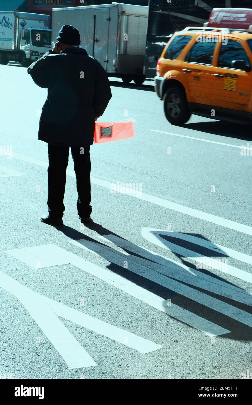 Rear view of a man standing in a parking lot with a parking sign flag ...