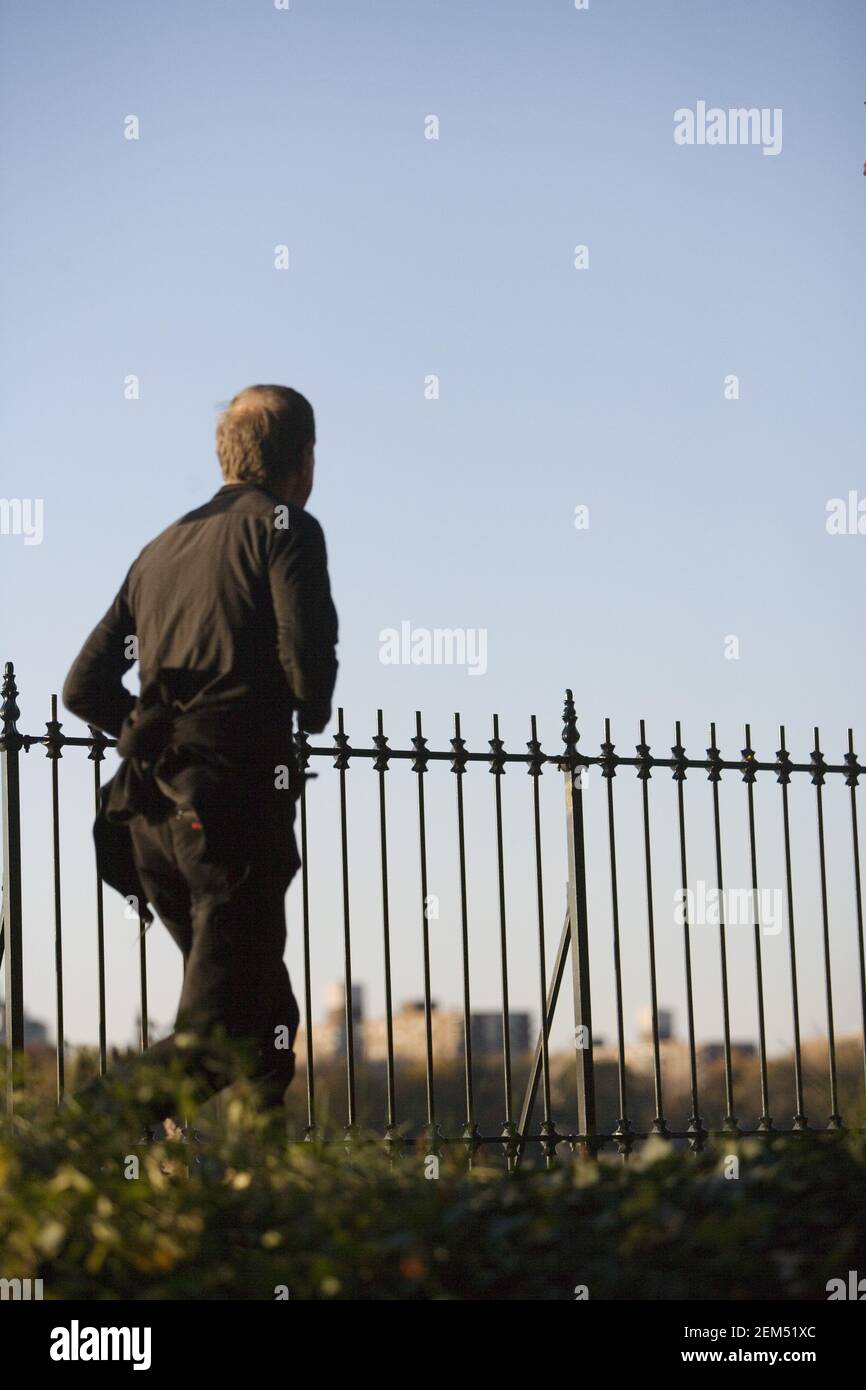 Rear view of a man walking near a fence Stock Photo - Alamy