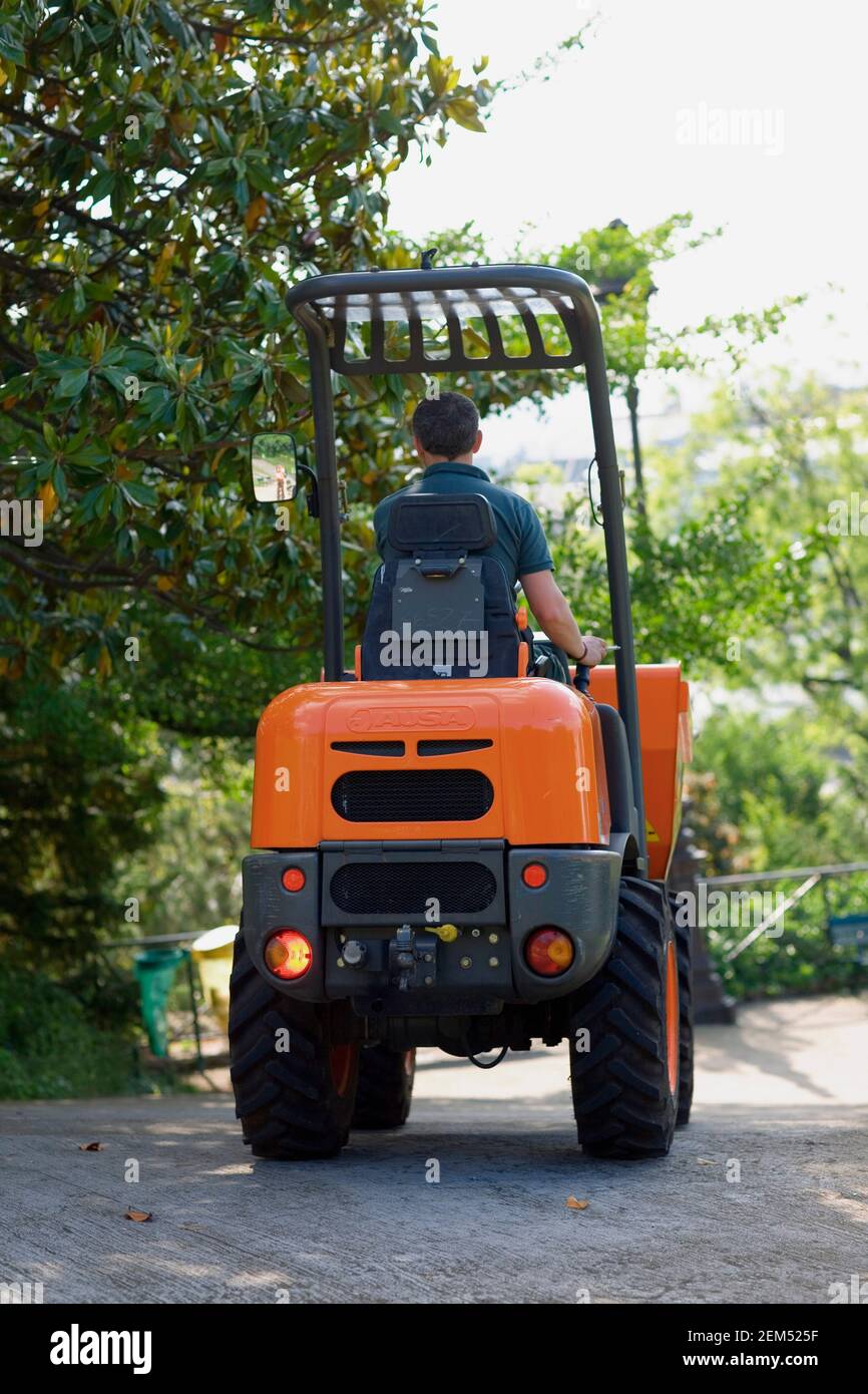Rear view of a man driving a tractor Stock Photo - Alamy