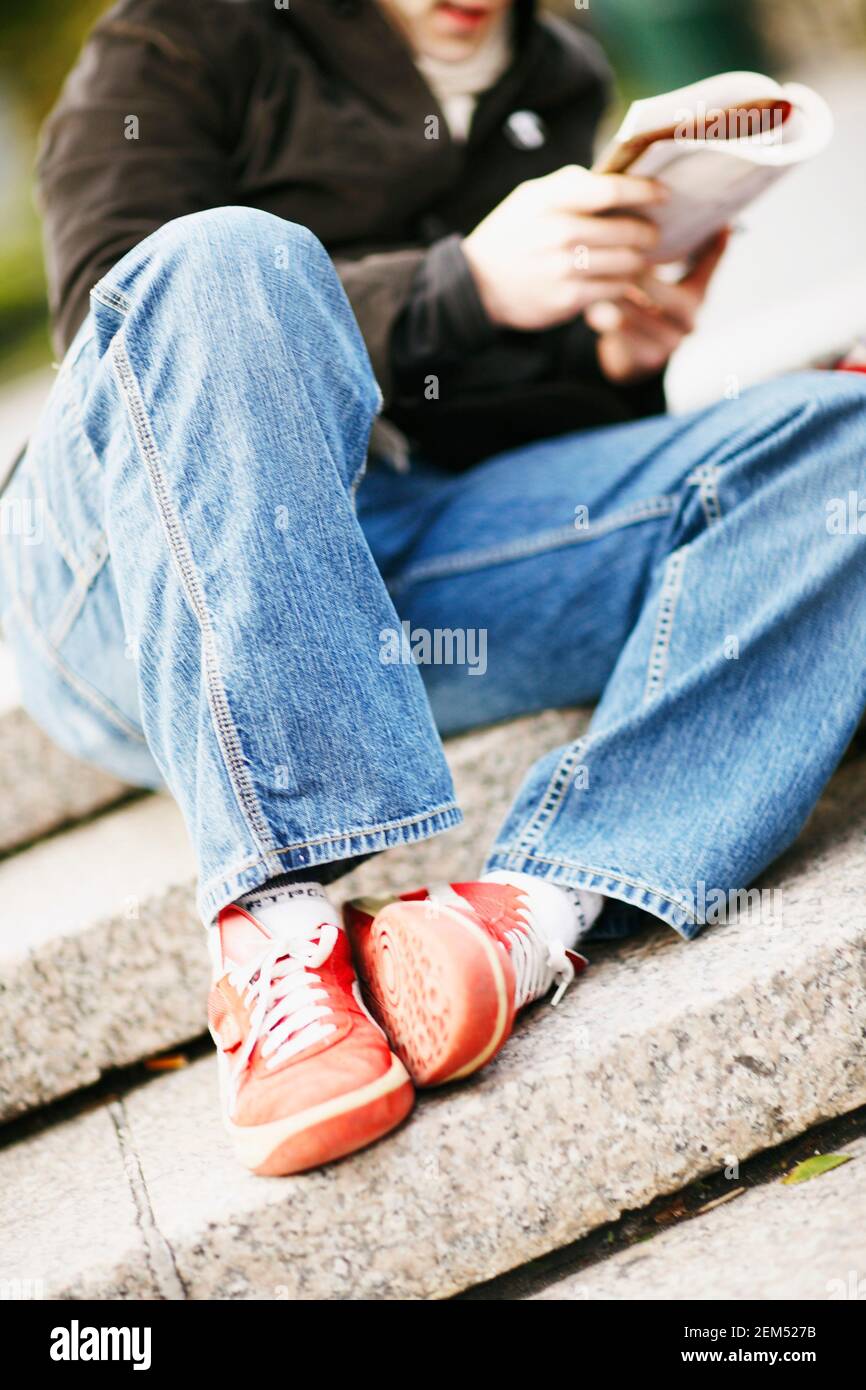 Low section view of a young man reading a book Stock Photo - Alamy