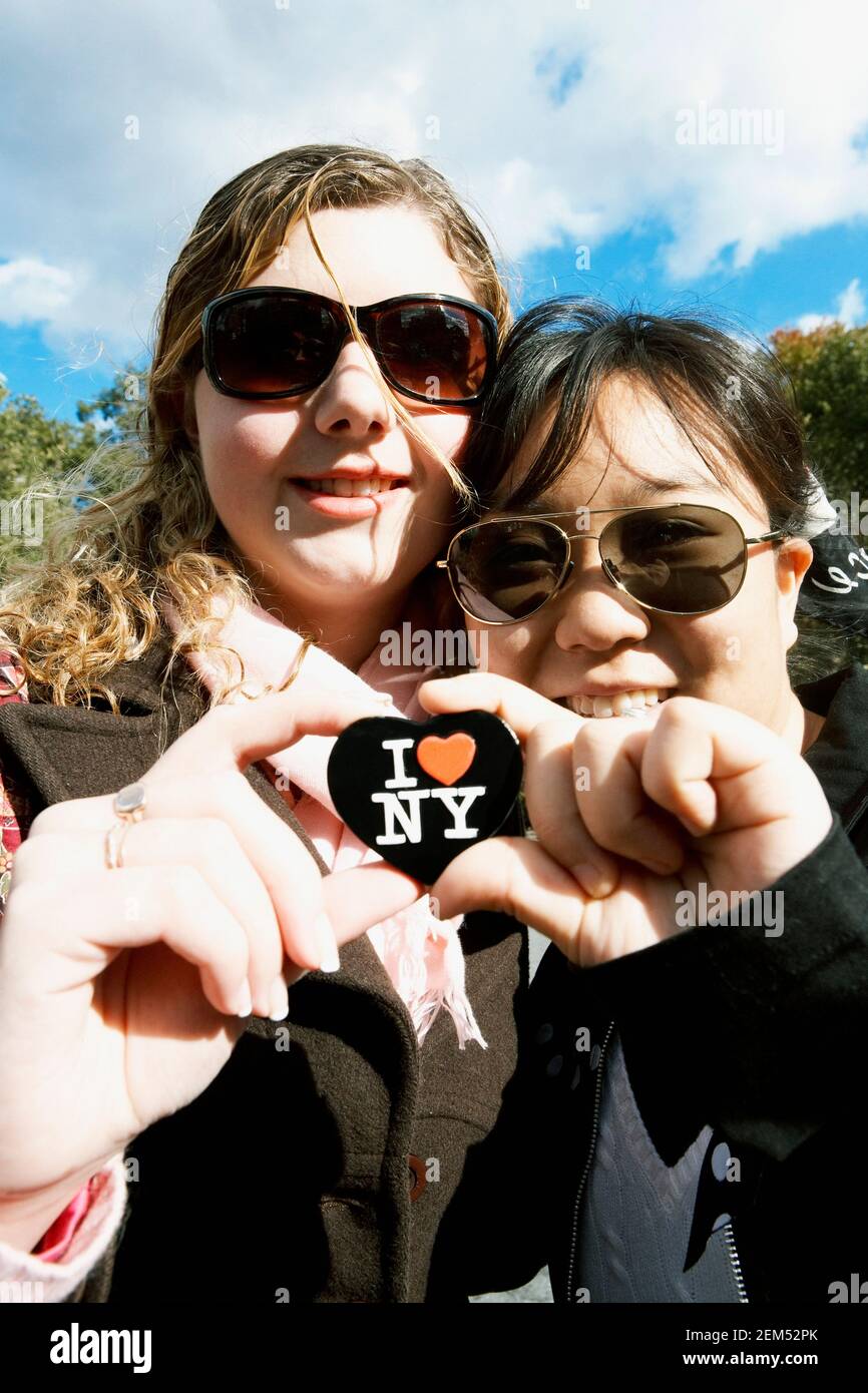 Portrait of two young women holding a heart shape token with I Love New ...