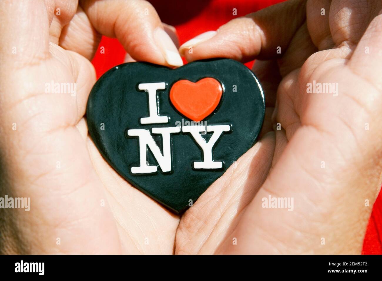 Close-up of a person's hand holding a heart shape token with I Love New ...