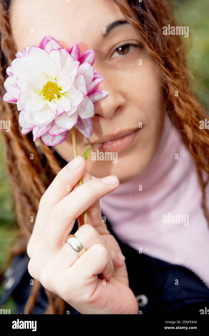 Portrait of a young woman covering her eye with a flower Stock Photo ...