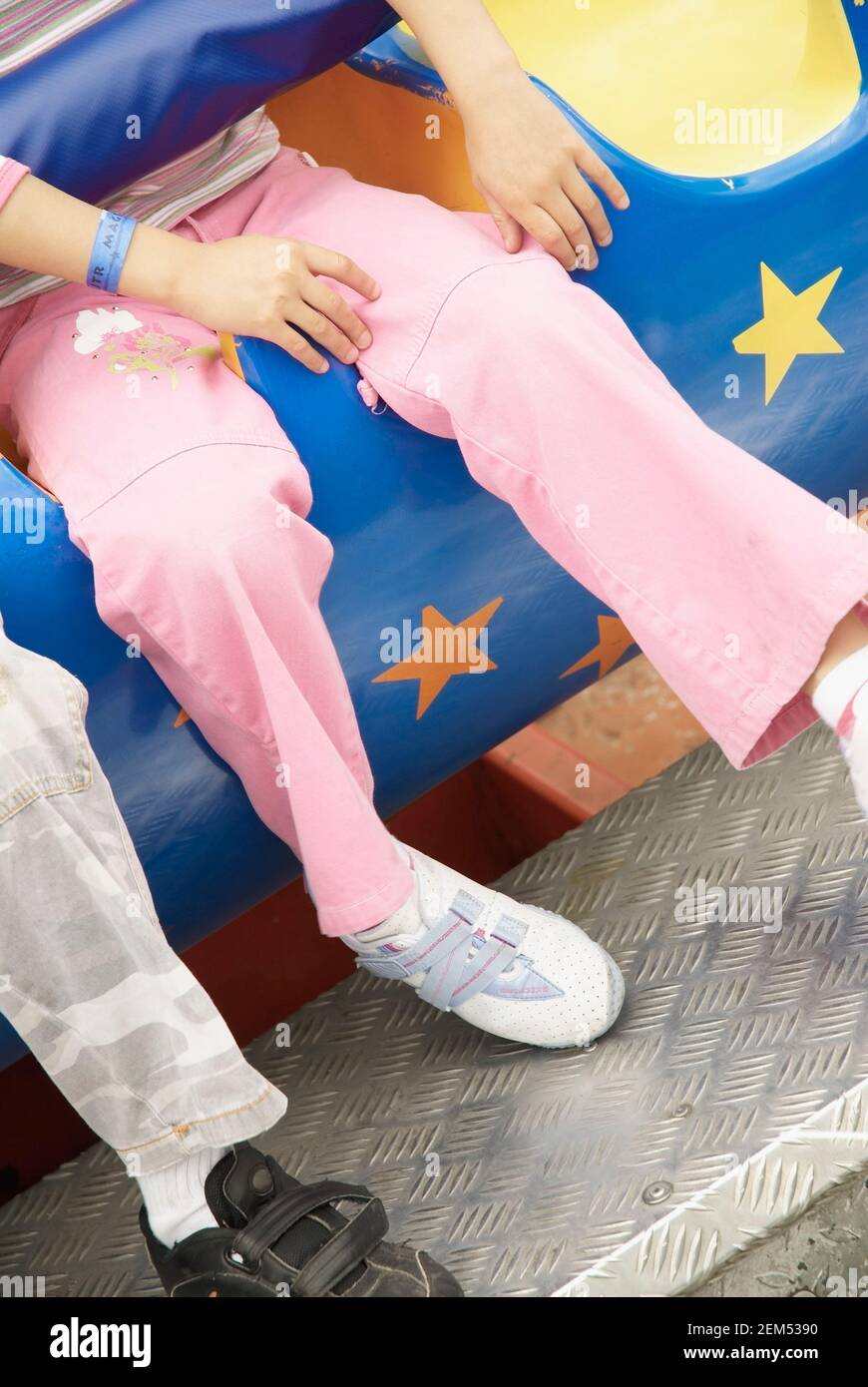 Low section view of a boy and a girl sitting on an amusement park ride ...